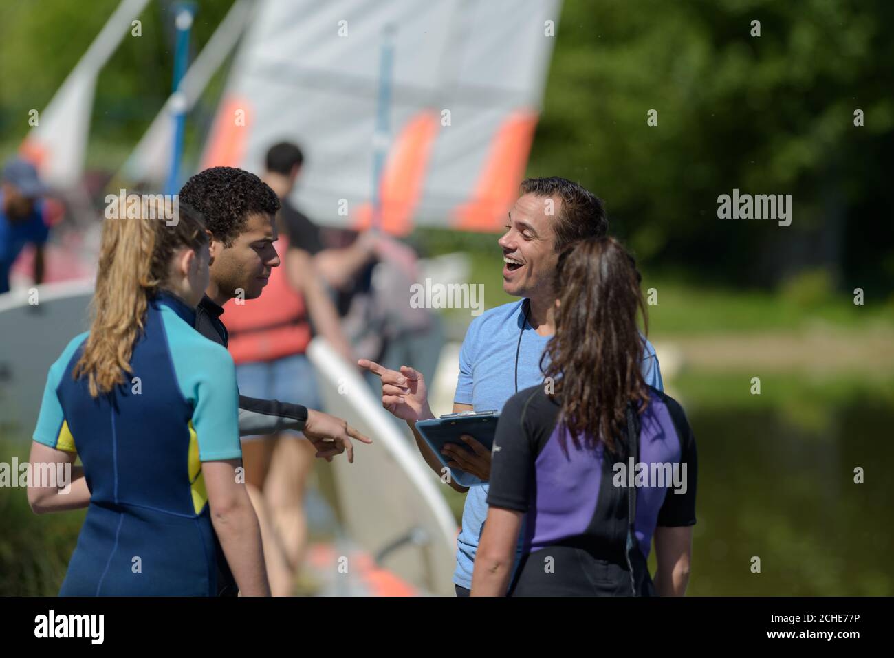 young people grouped around sailing instructor Stock Photo - Alamy