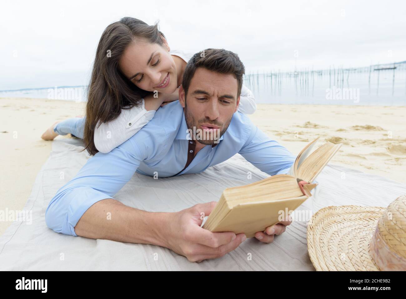 couple on beach reading book Stock Photo - Alamy