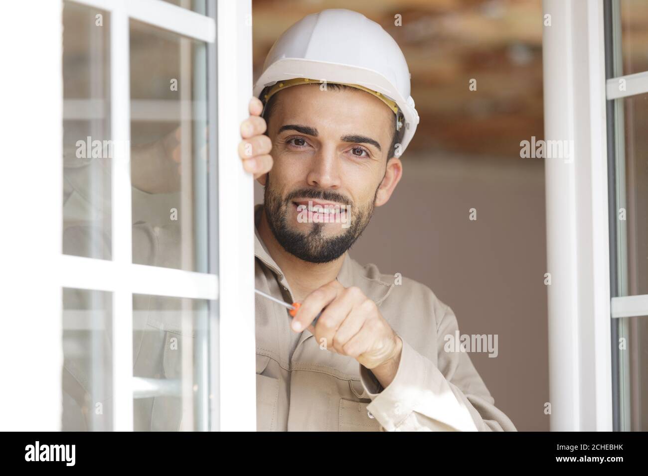 worker screws frame of plastic door Stock Photo - Alamy