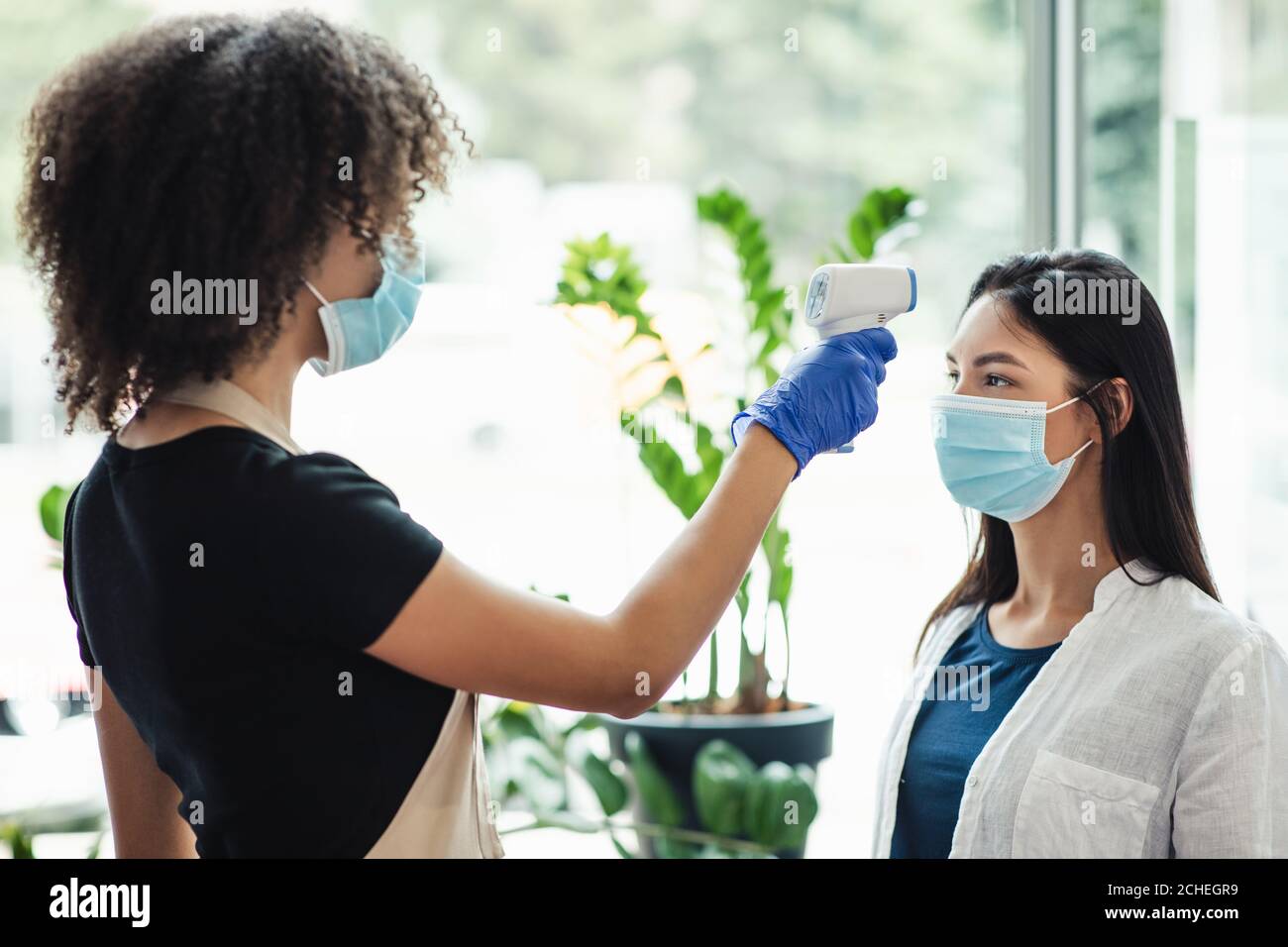 Manager checking body temperature of client at beauty salon, side view ...