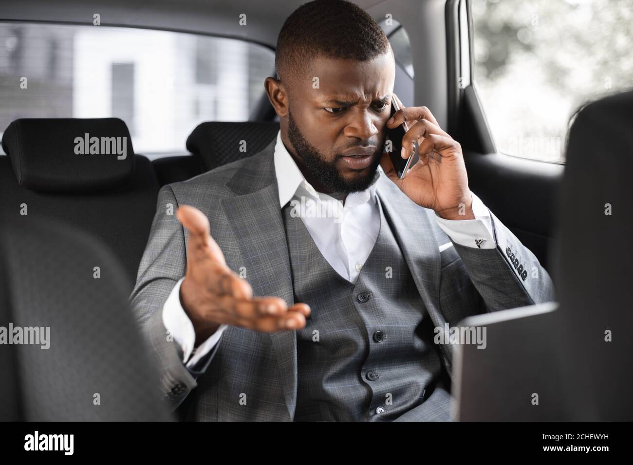 Angry african american businessman talking on phone in car Stock Photo ...