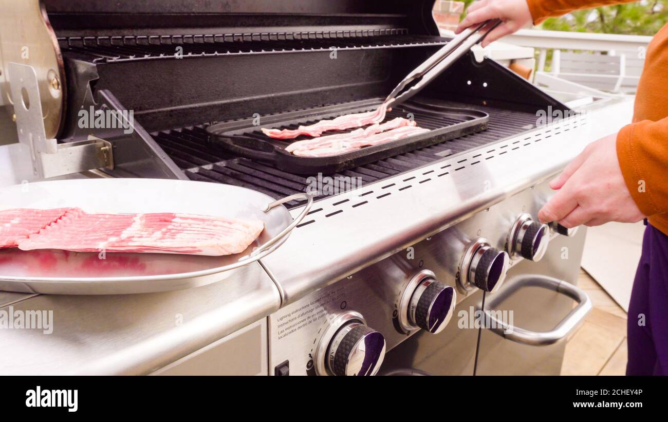 Cooking bacon stips on an outdoor gas grill Stock Photo - Alamy