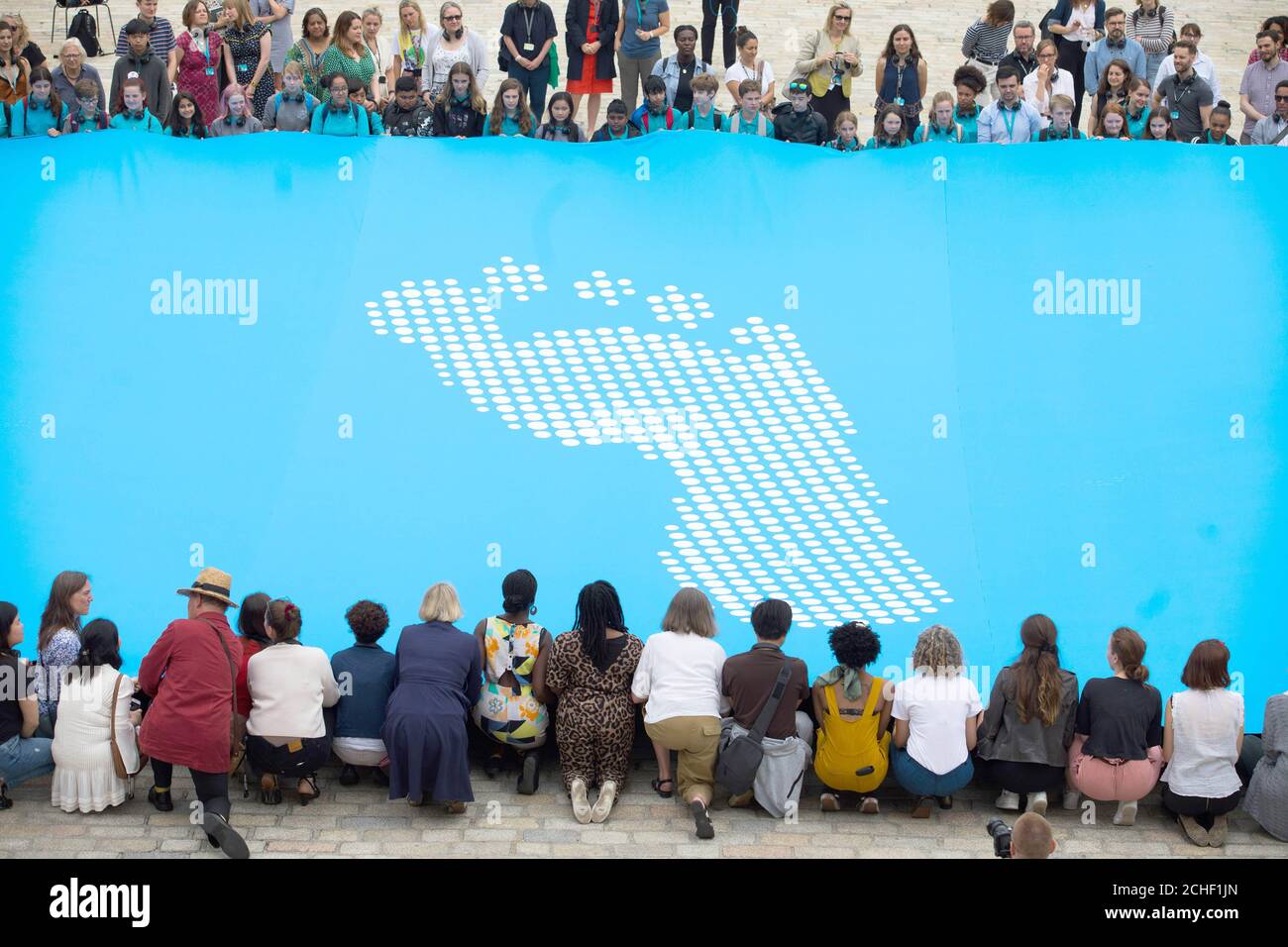 EDITORIAL USE ONLY A group of young people hold a giant version of a ...