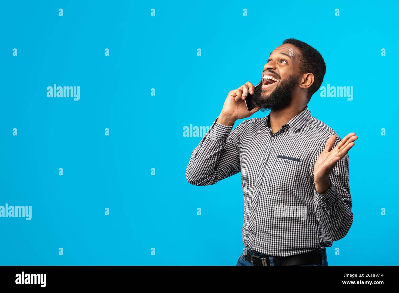 Smiling black man talking on the phone, blue background Stock Photo - Alamy