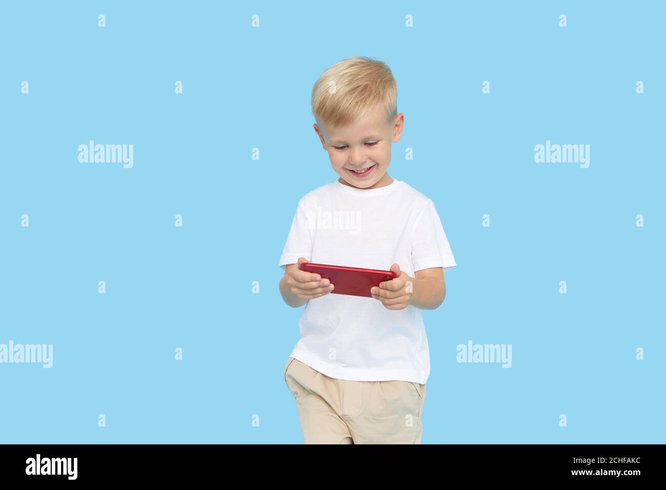 Cute smilling child boy with smartphone on blue background. Advertising ...