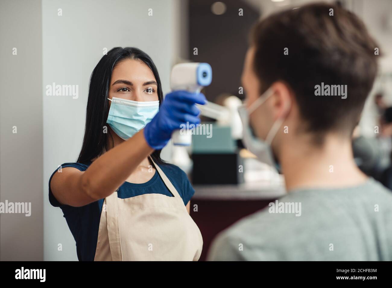 Expert using infrared thermometer to check body temperature of male ...