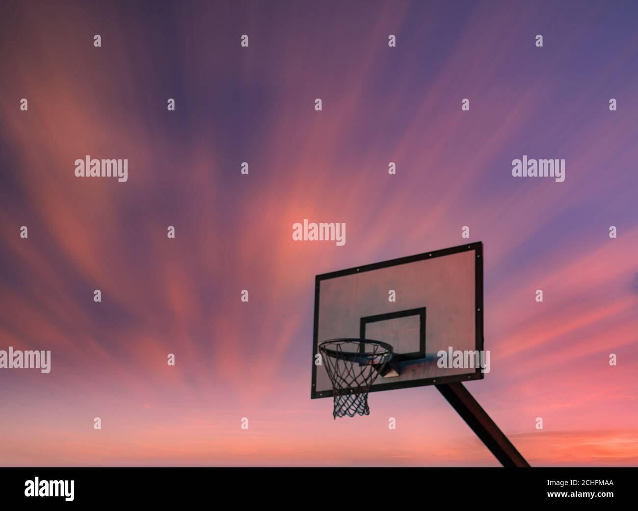 Isolated basketball hoop at sunset with long exposure dramatic red sky ...