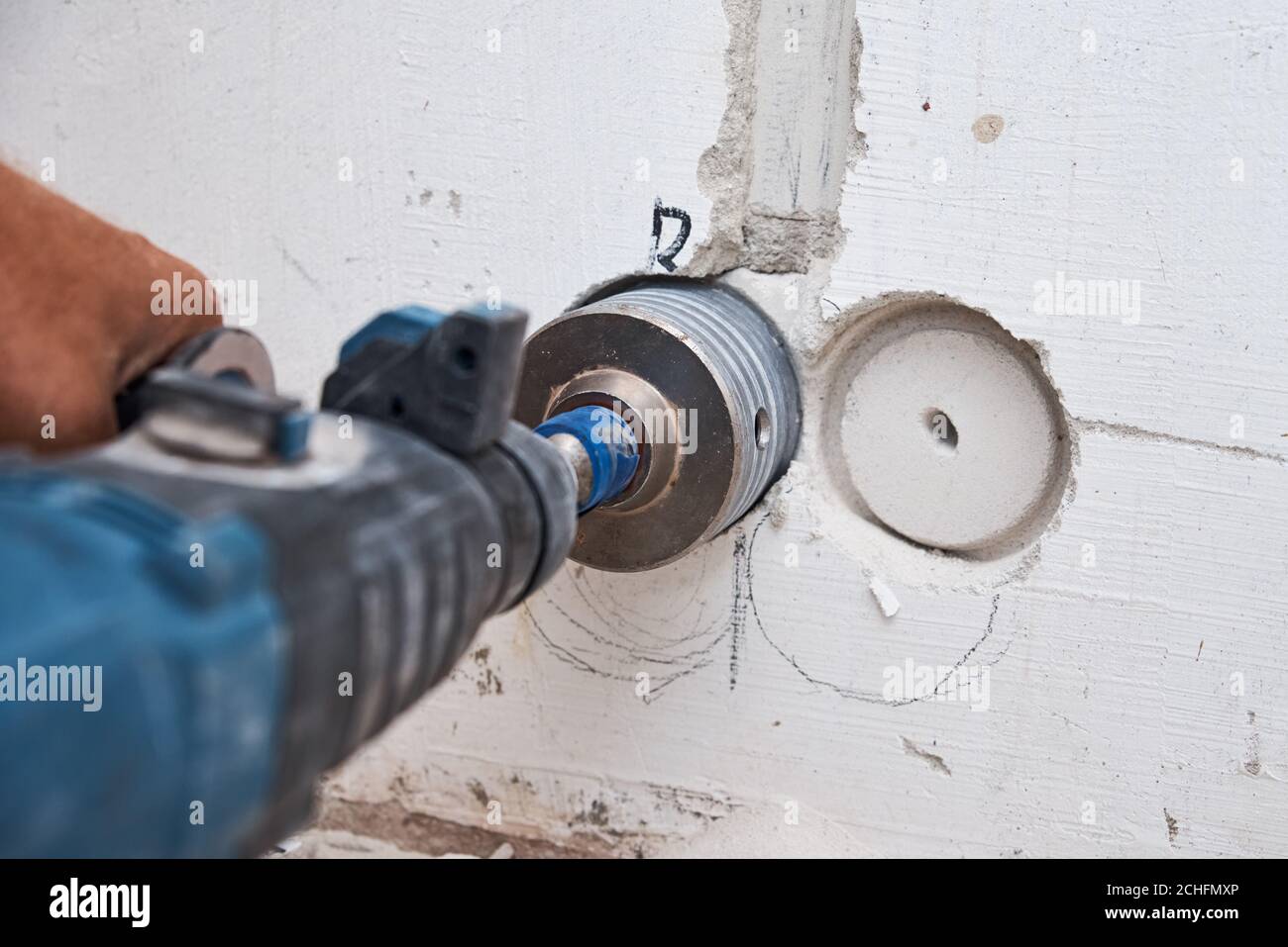 Builder with hummer drill perforator drills hole in the wall Stock ...