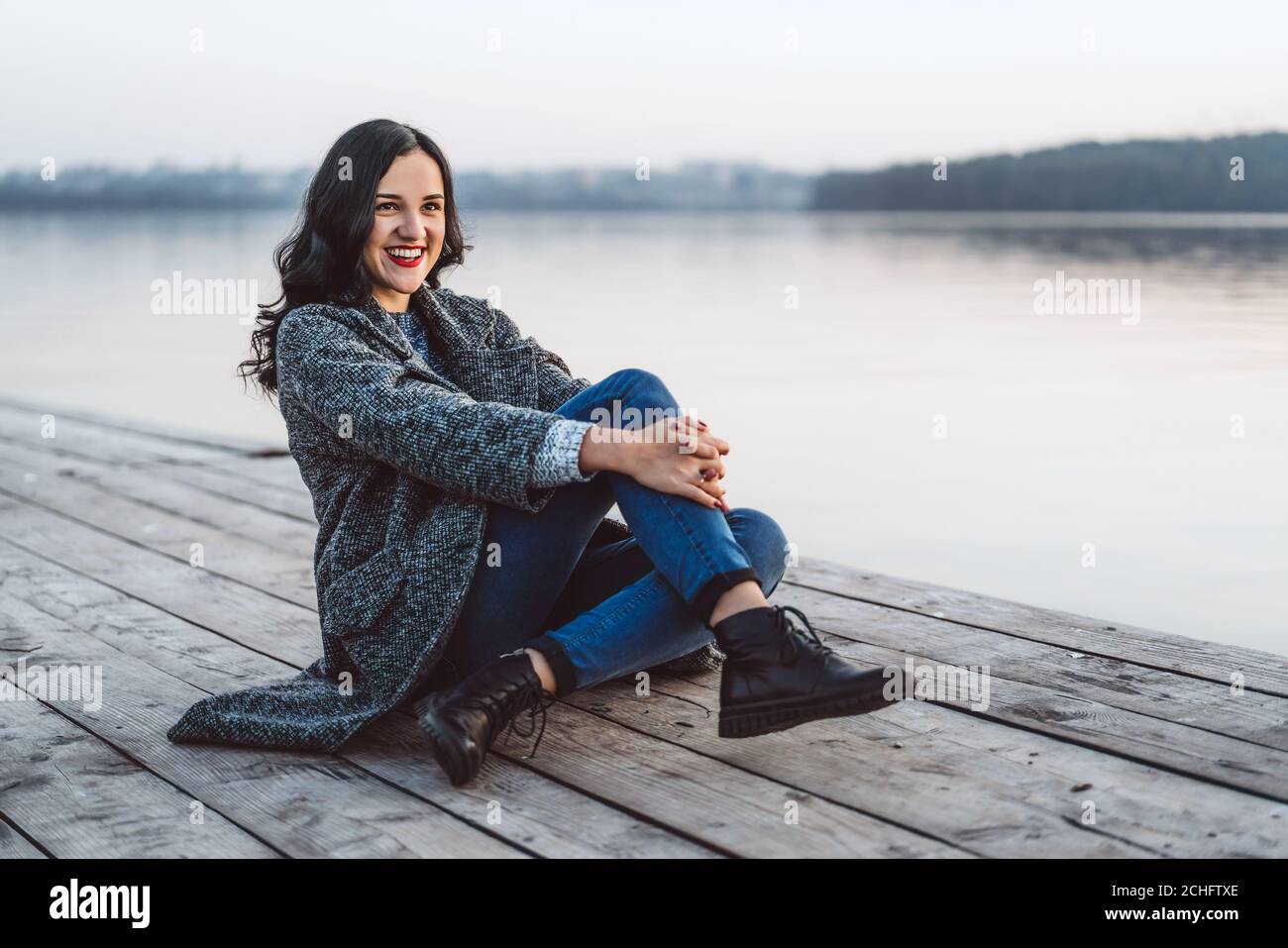 Pretty long hair brunette girl relaxing on the pier near lake Stock ...