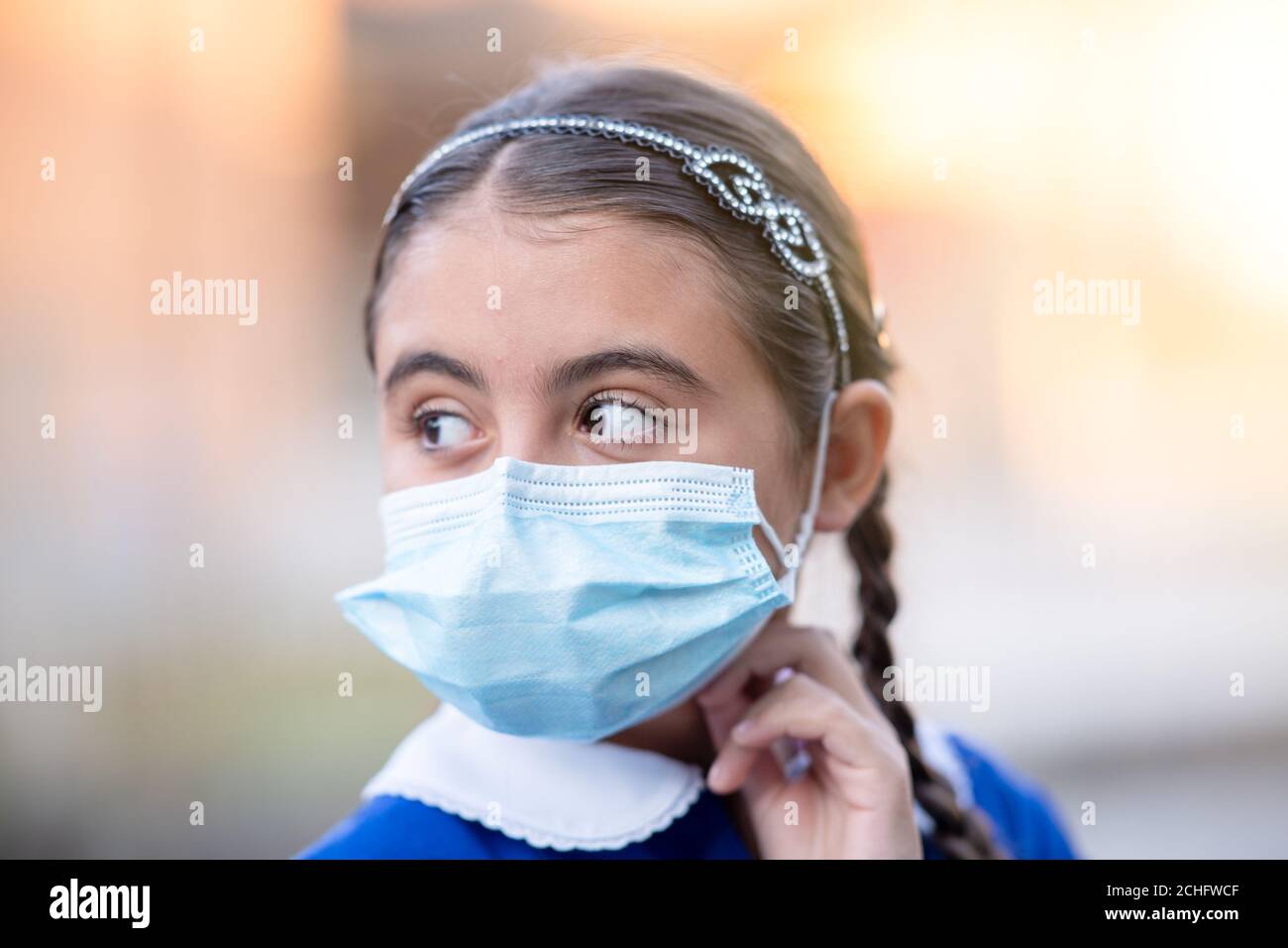 Portrait of young girl returning to school after pandemic, wearing mask ...