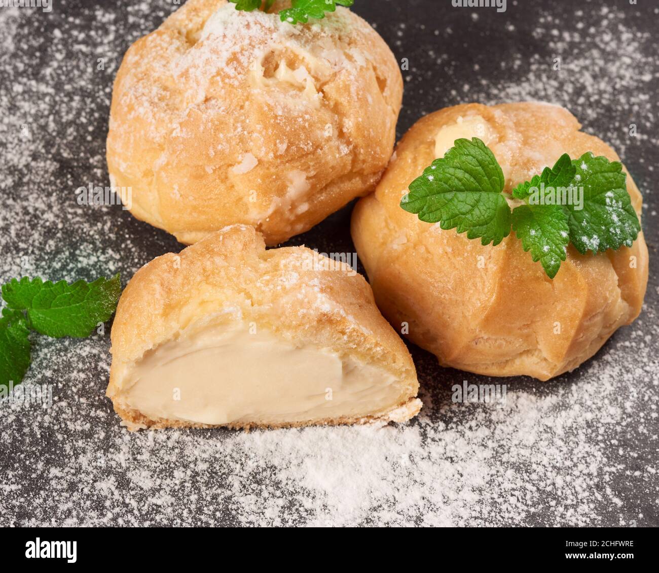 custard eclair cut in half and sprinkled with icing sugar, close up ...
