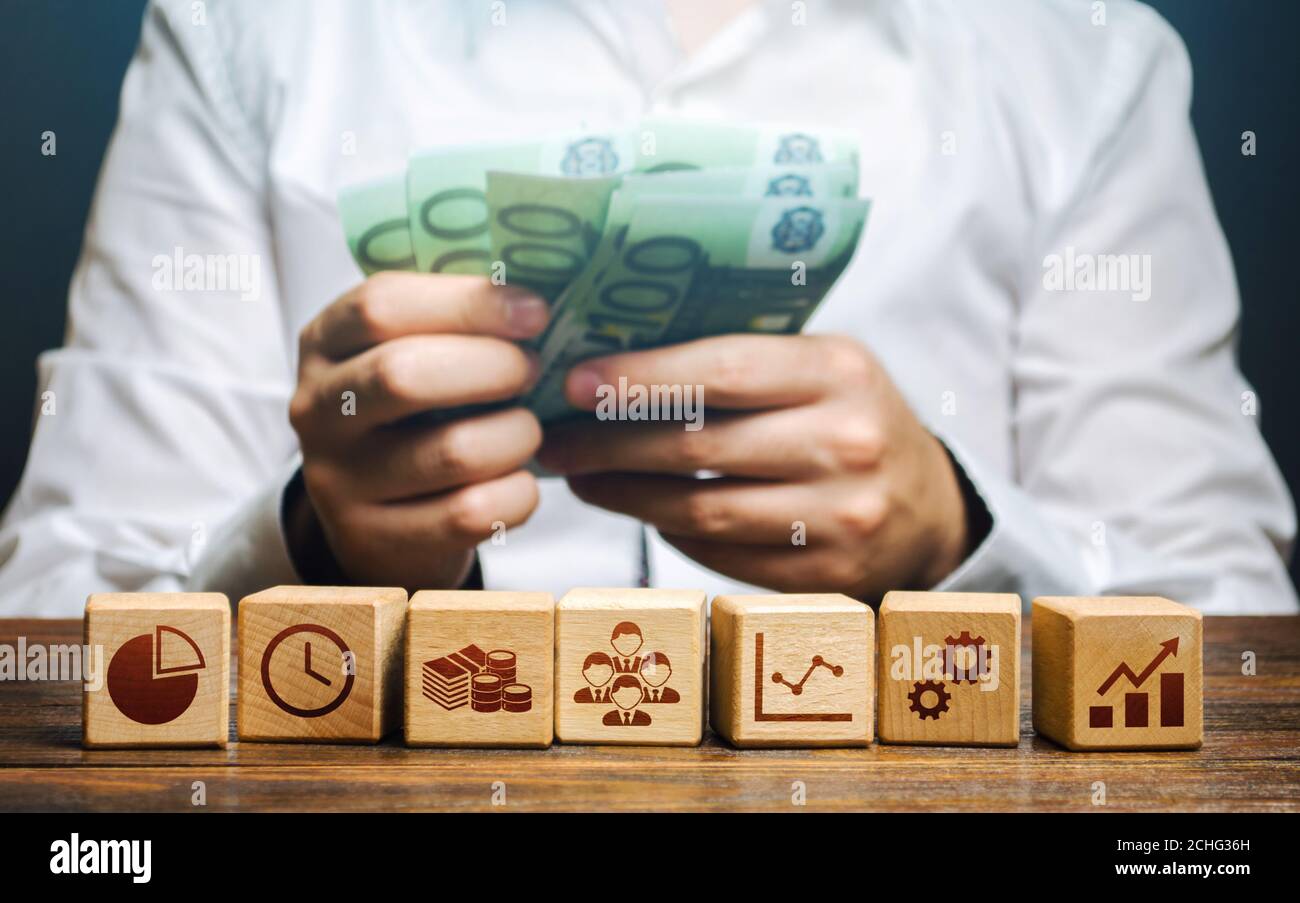 A man is counting money and blocks with business attributes. Good ...