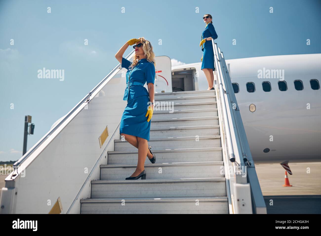 Two beautiful stewardesses standing on airplane stairs Stock Photo - Alamy