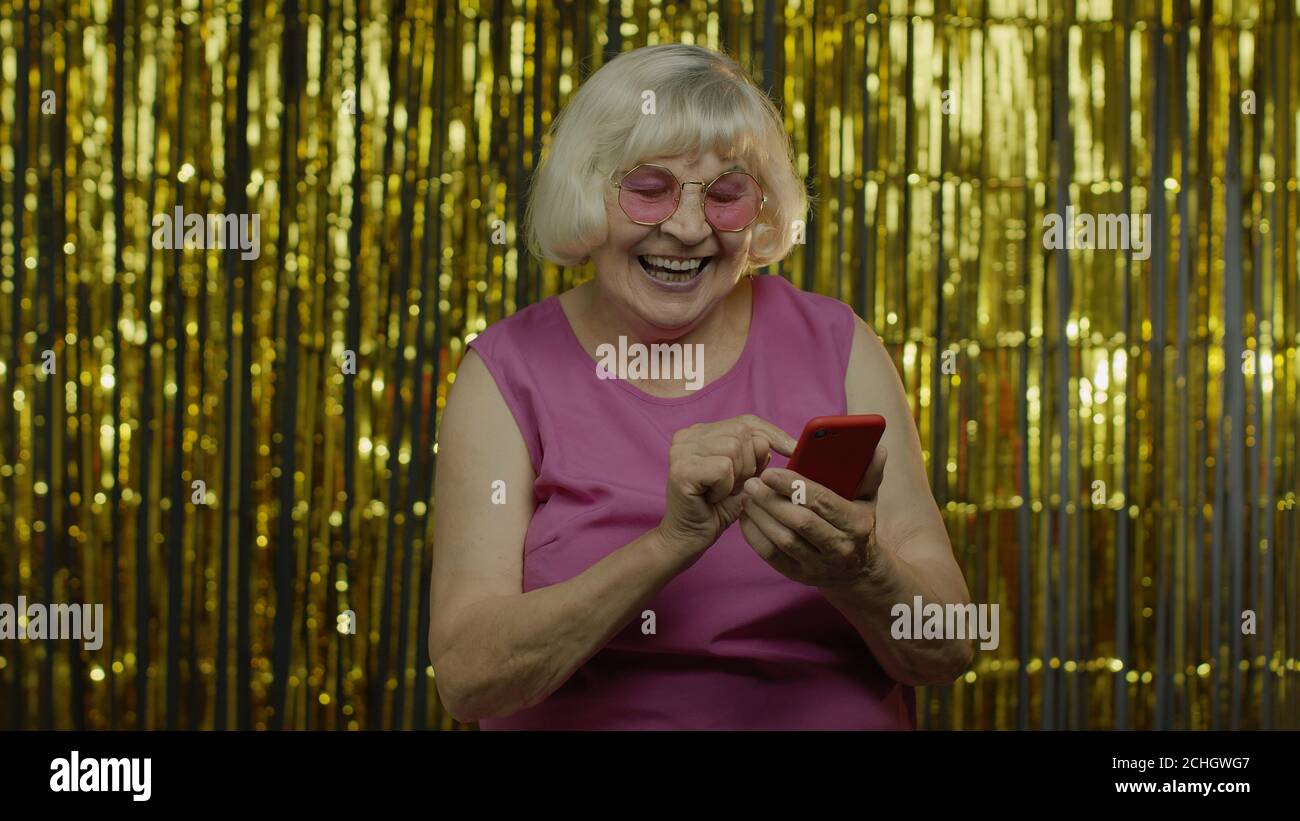 Stylish happy senior old woman typing message on mobile phone and ... Stylish happy senior old woman typing message on mobile phone and ...