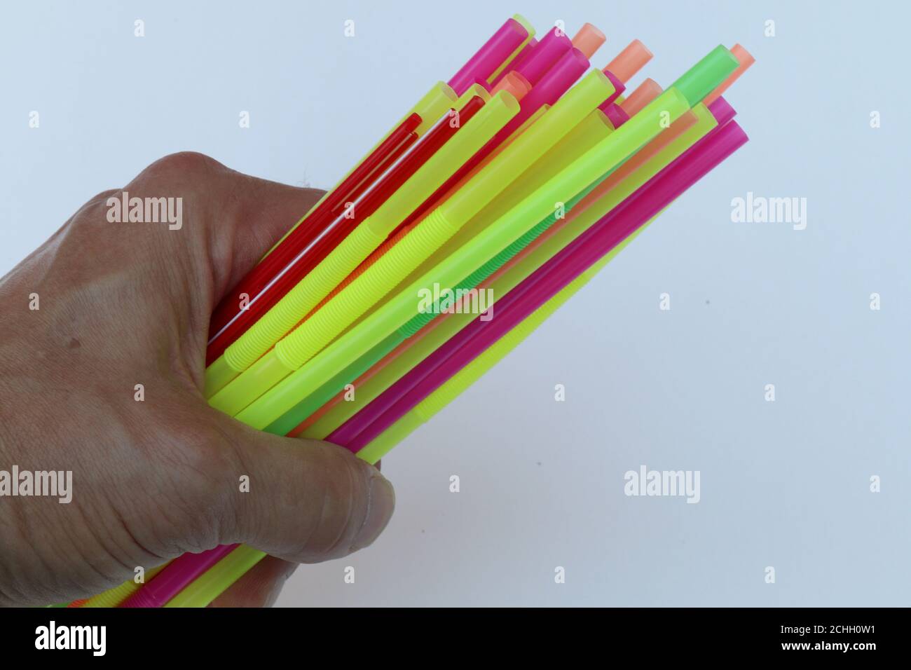 Plastic straws in a mans hand on the left side with space for text on ...