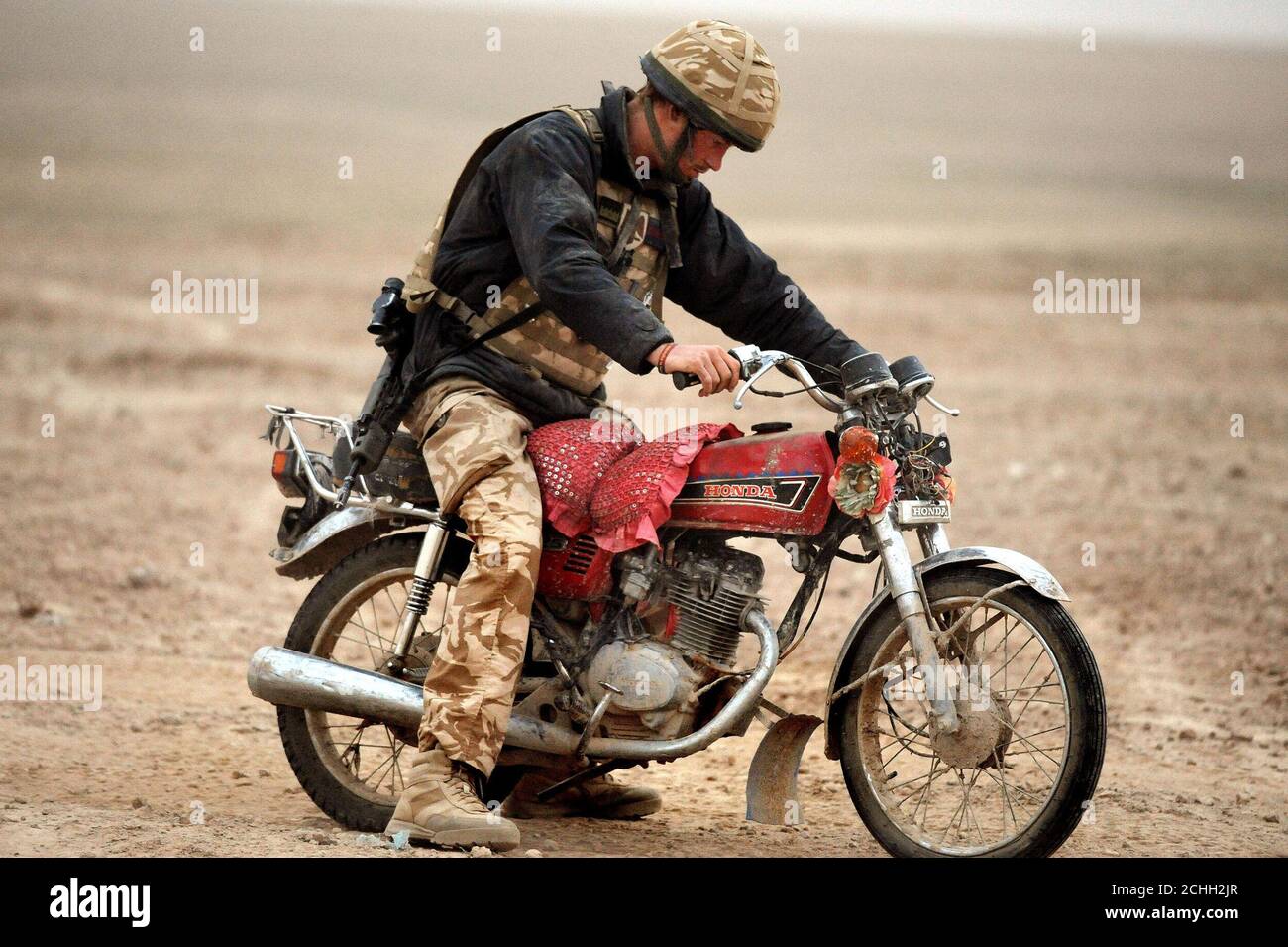 Prince Harry tries to push start an abandoned motorcycle in the desert ...
