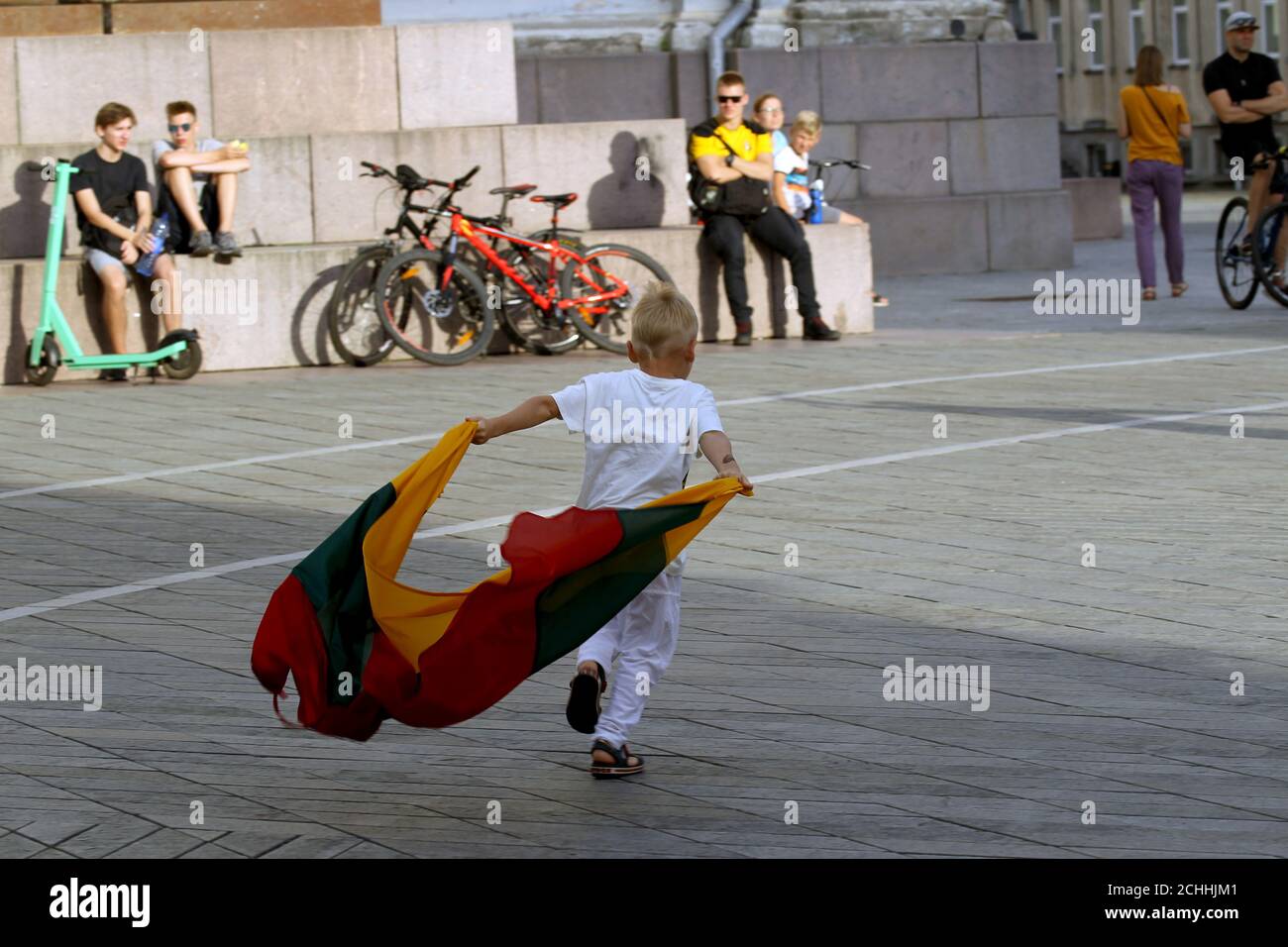 A child carries a fluttering tricolor Lithuanian flag outdoors. Kaunas ...