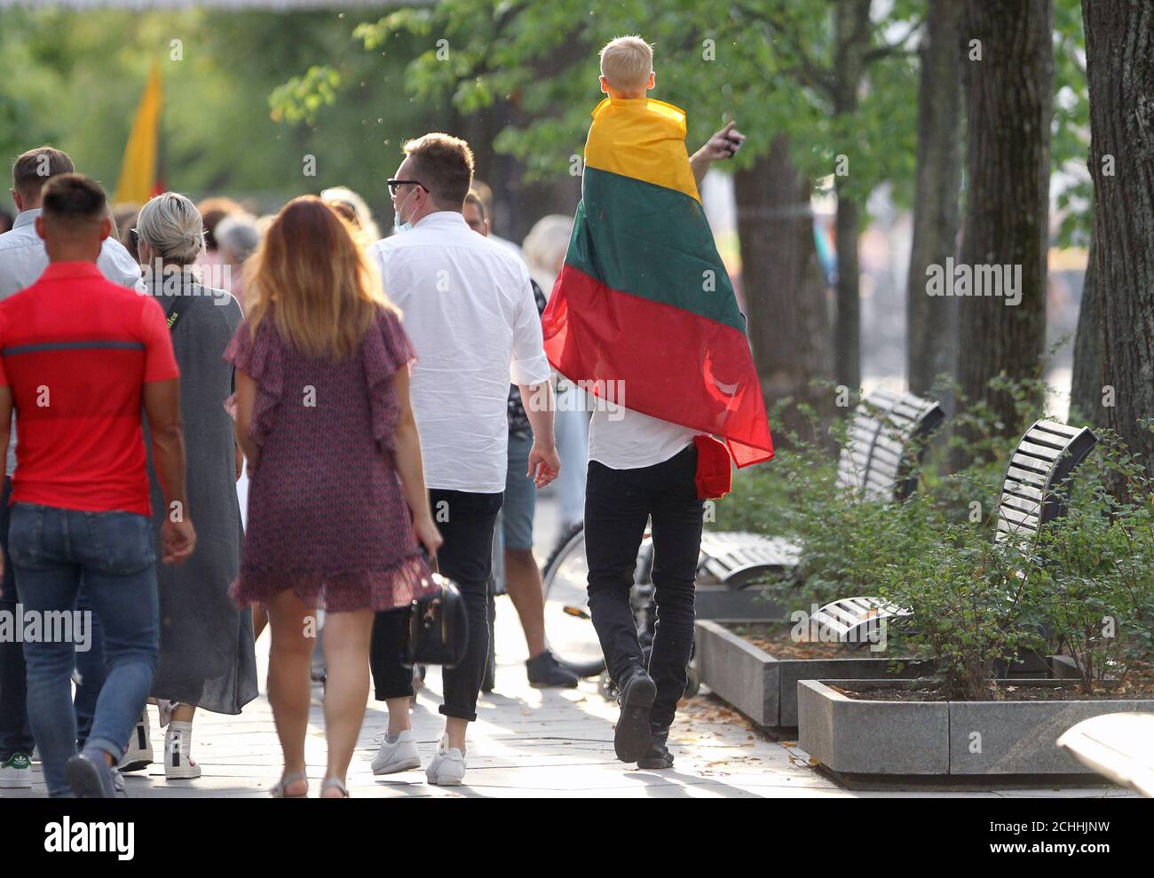 A child carries a fluttering tricolor Lithuanian flag outdoors. Kaunas ...
