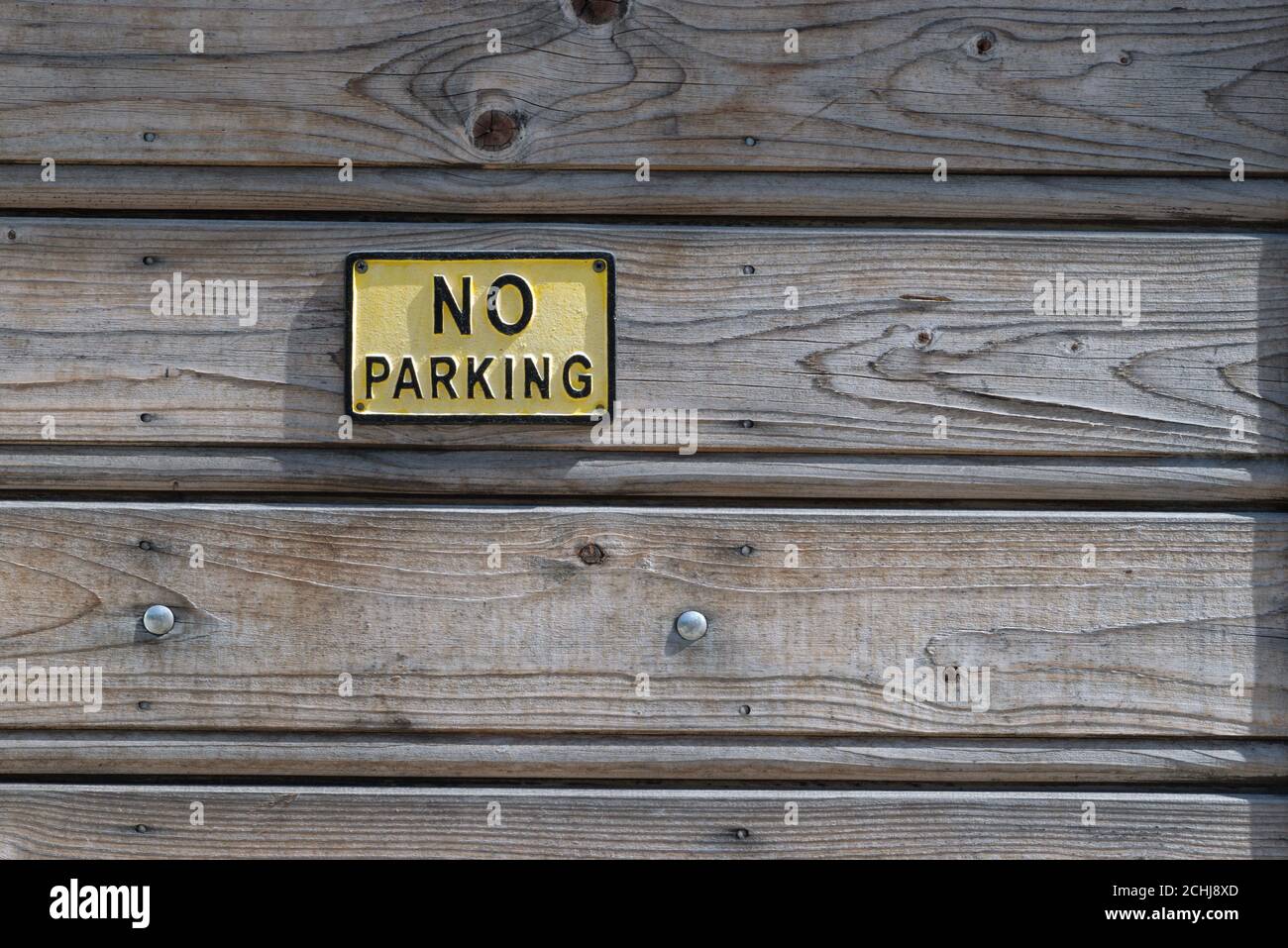 Yellow no parking sign on wooden door or fence Stock Photo - Alamy