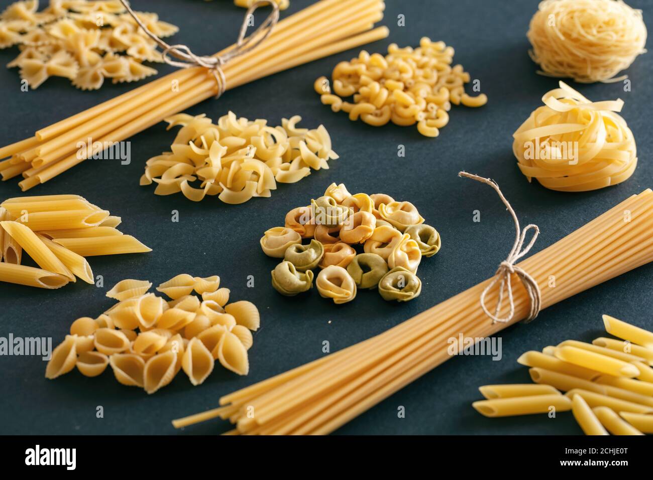 Pasta cooking concept. Raw pasta shapes variety on black background ...