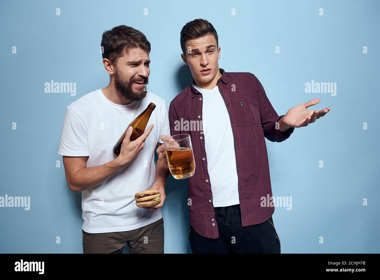 Two cheerful drunk friends drinking beer lifestyle emotions on a blue ...