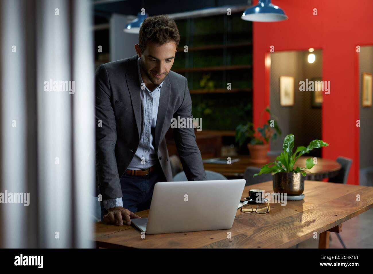 Businessman standing at his office desk working on a laptop Stock Photo ...