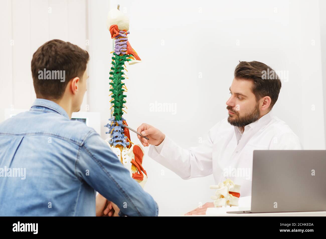 Doctor showing flexible spine model to his patient and explains the ...