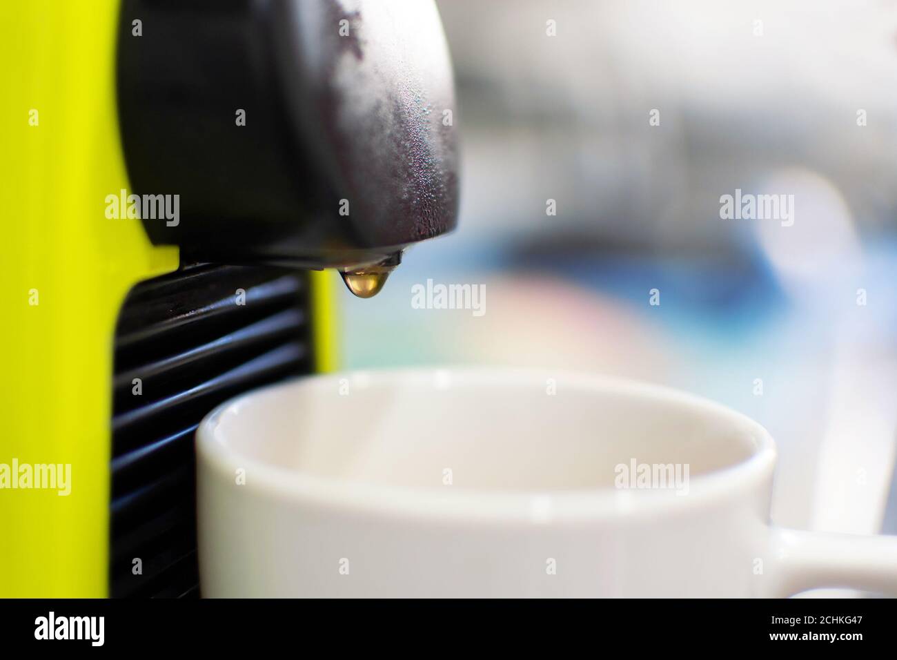 Coffee machine pouring liquid slowly in a cup at home kitchen. Drop ...