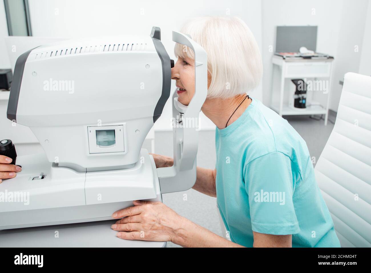 Elderly woman checking eyesight in a clinic using diagnostic ophthalmic ...