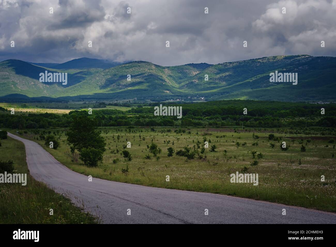 Beautiful country valley road before a thunderstorm at sunset. Mountain ...