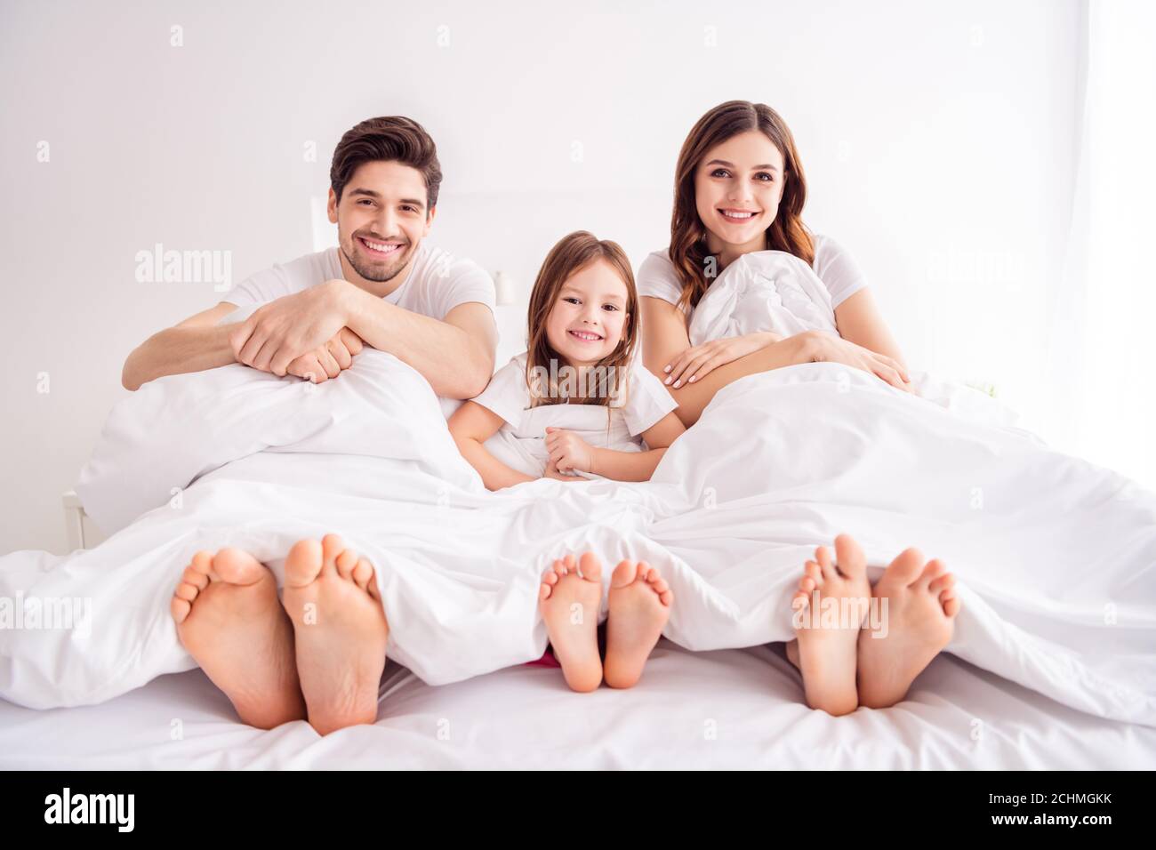Photo of happy family barefoot legs mommy daddy kid lying sheets ...
