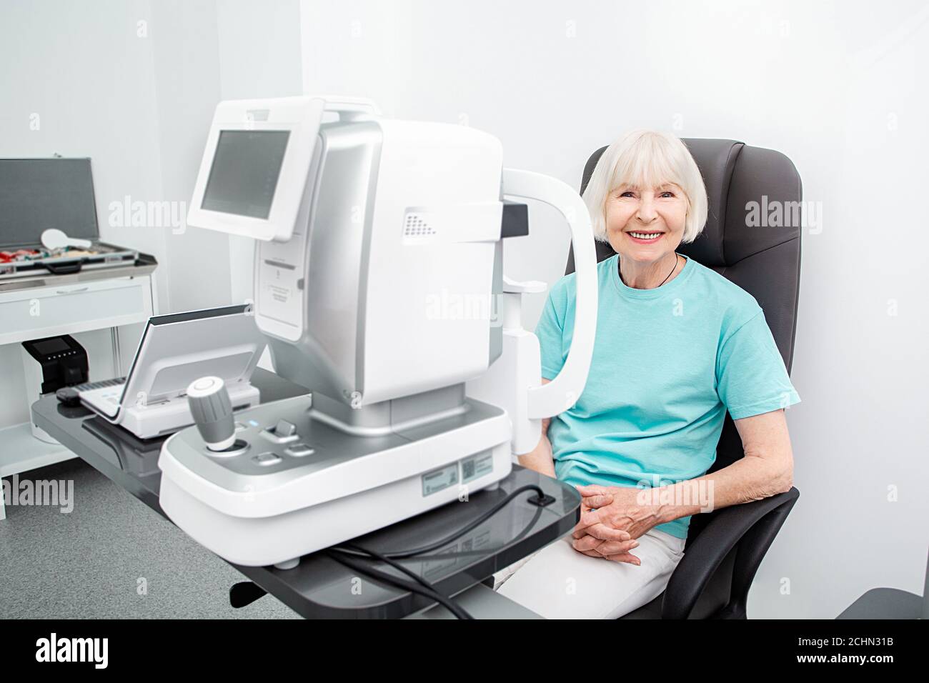 Smiling old woman checking eyesight in a clinic using diagnostic ...