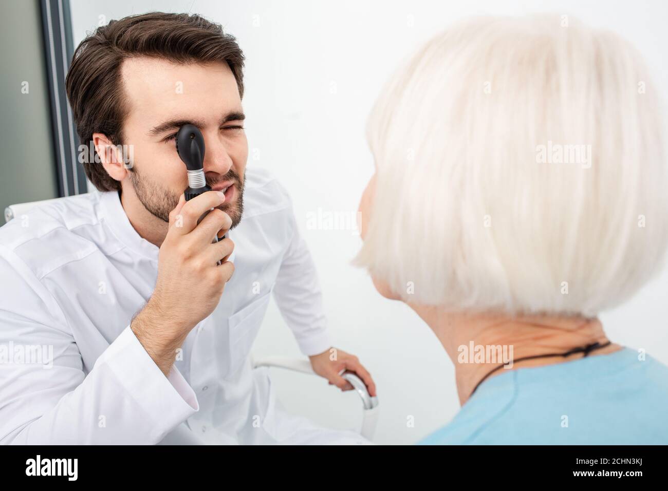 doctor optometrist examining old woman's eyes with an ophthalmoscope ...