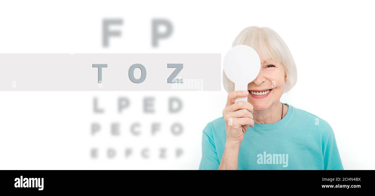 Senior woman having an eye exam with one eye covering using a special ...