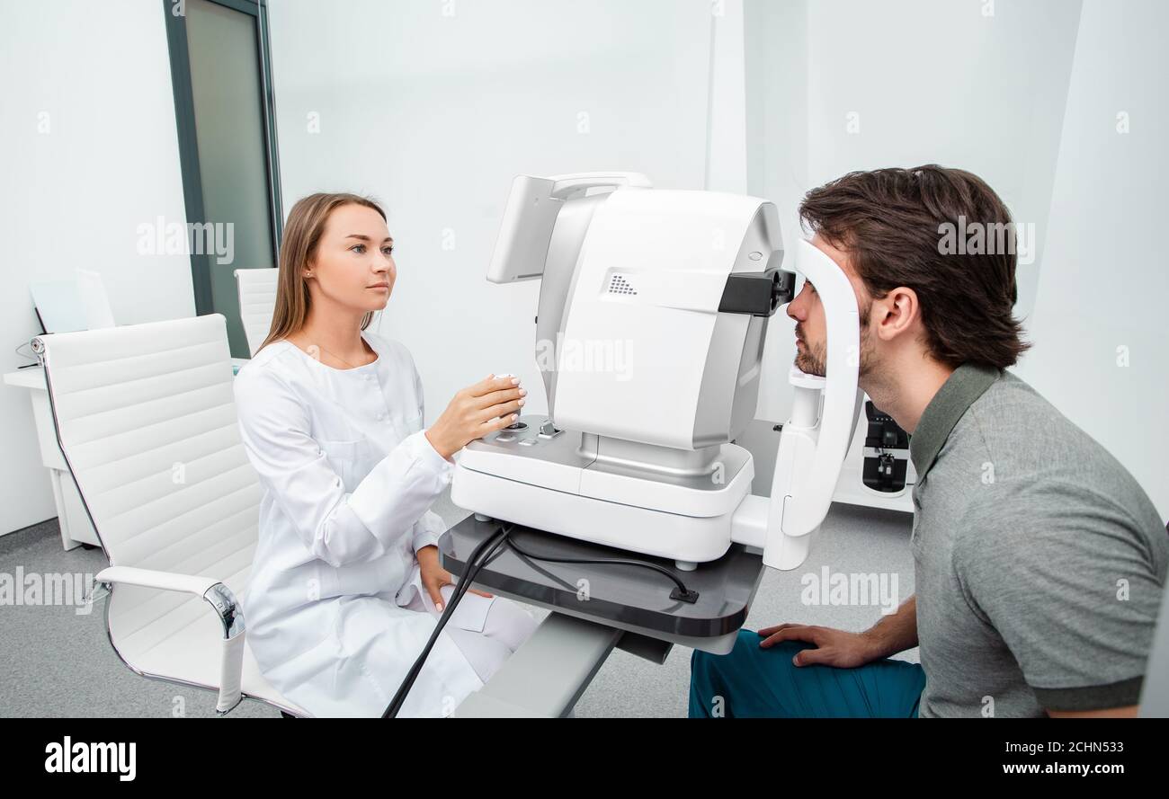 Optometrist using autorefractor check patient vision. Eye exam of adult ...