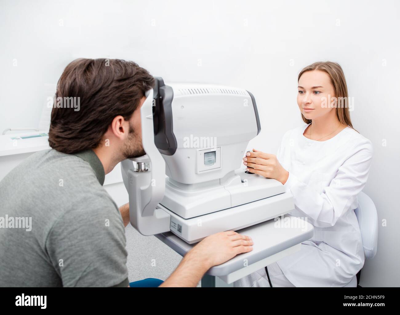 Optician woman checking eyesight to male patient in a clinic using ...