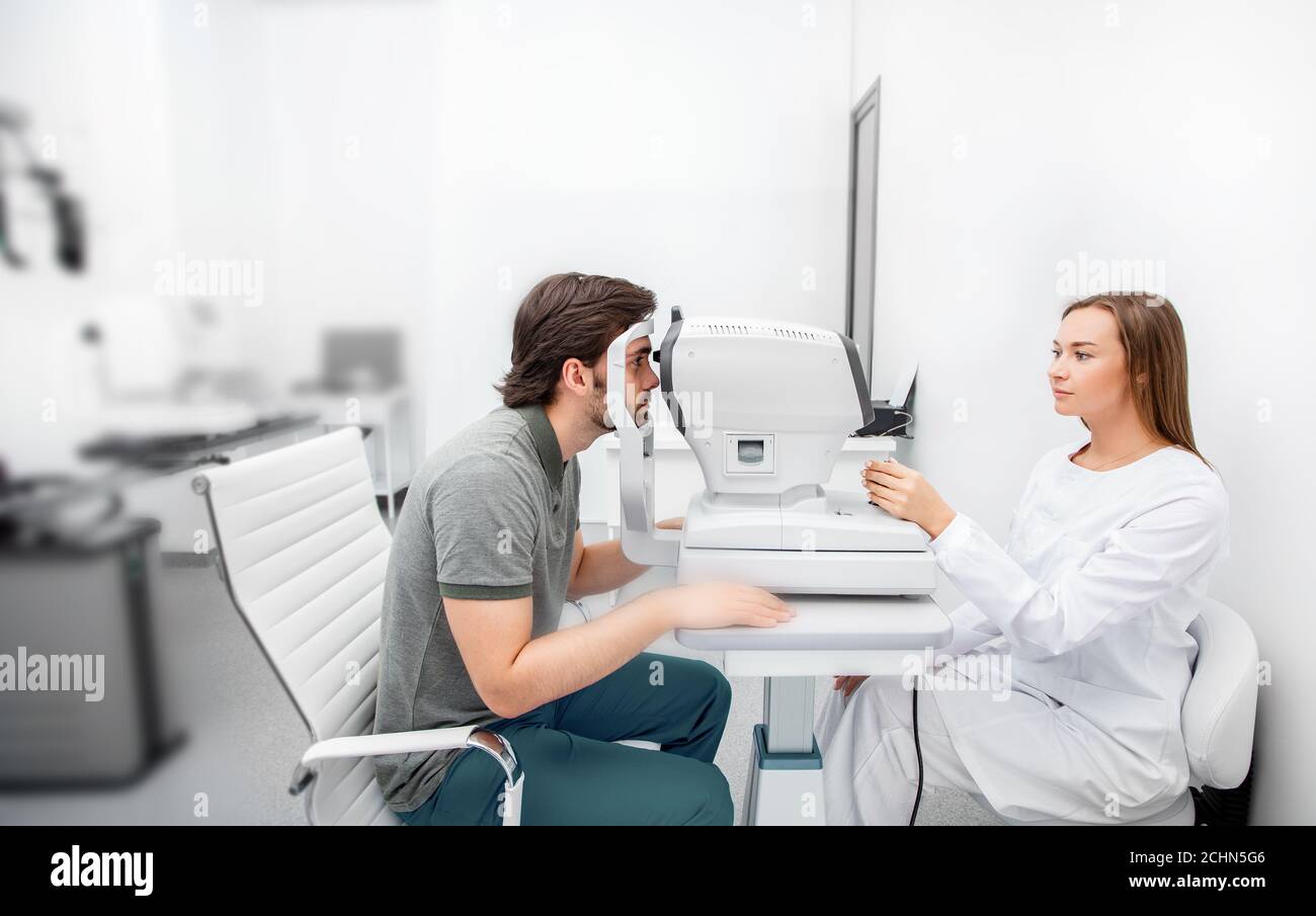 Experienced ophthalmologist woman using an autorefractor calculates the ...