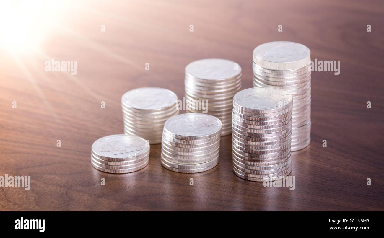 Stacks of Silver coins on a wood table top with light shining Stock ...