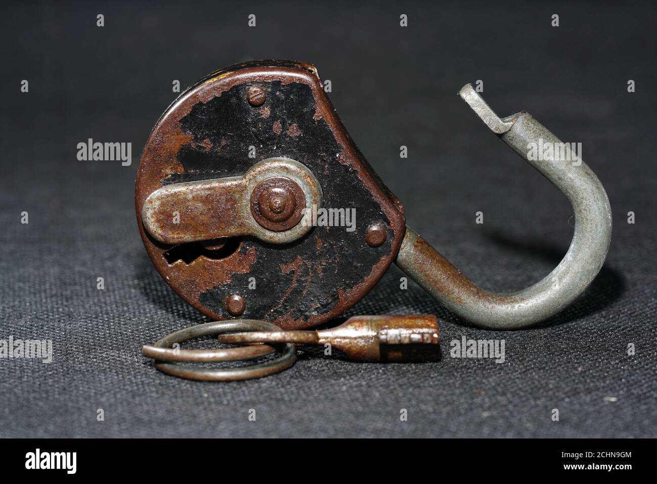 Closeup shot of an old rusty padlock with a key on a dark background ...