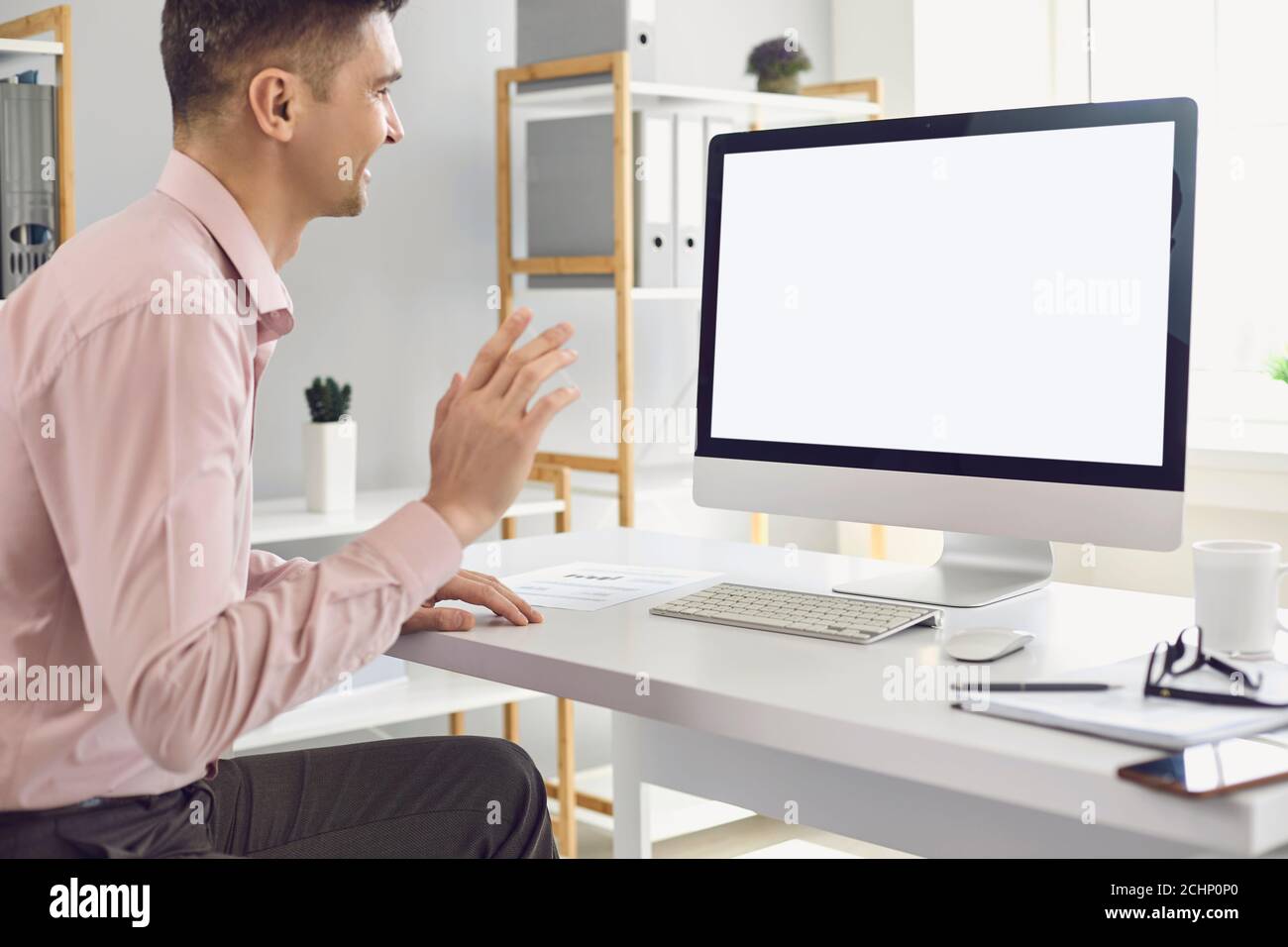 Man using personal desktop computer for teleconference and waving hand ...