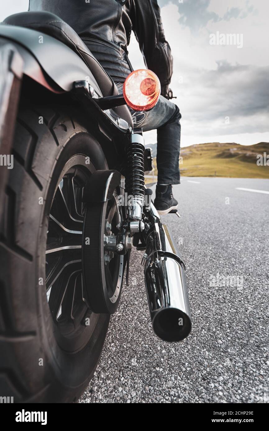 Driver riding motorcycle on an asphalt road in mountain, detail of rear ...
