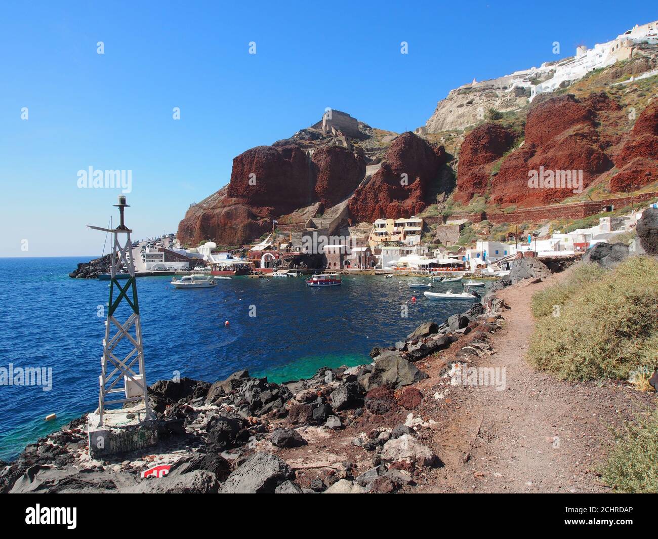 Pathway leading around Amoudi Bay beneath a clear blue sky and against ...