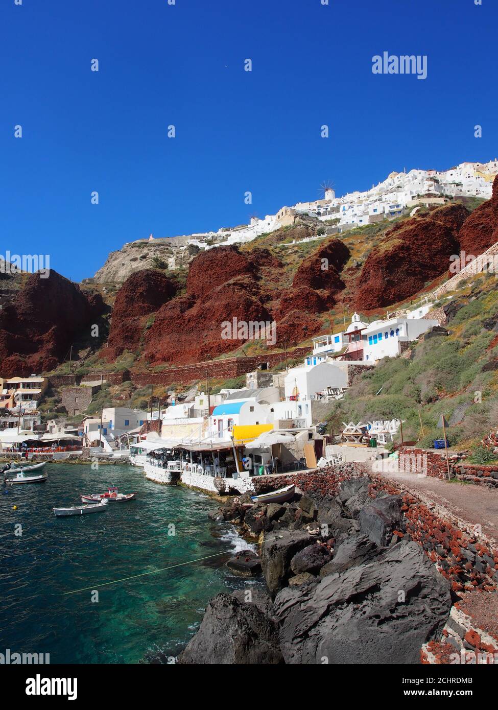 Boats moored in the clear sea of Amoudi Bay against clear blue sky and ...
