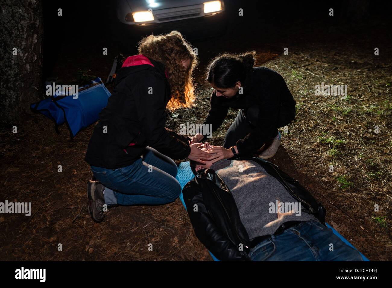 Field First Aid Training. The man is lying on the ground. Two women ...