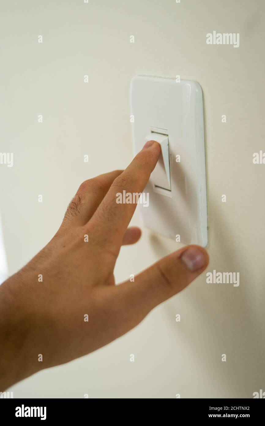Hand pushing a white switch on a white wall Stock Photo - Alamy