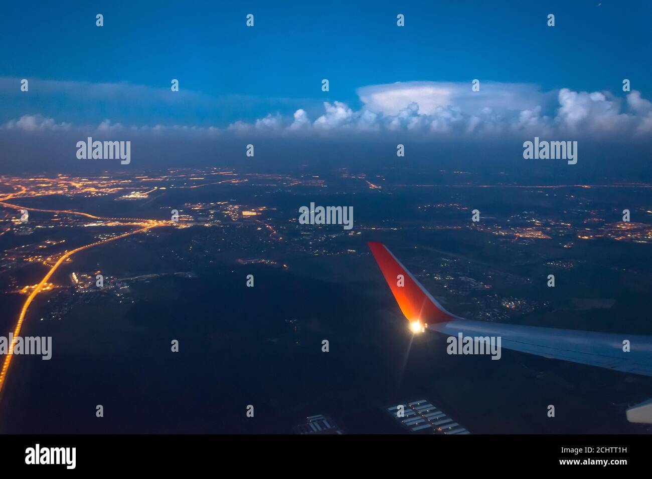 Wing view fly over the city at night and storm clouds at the horizon ...