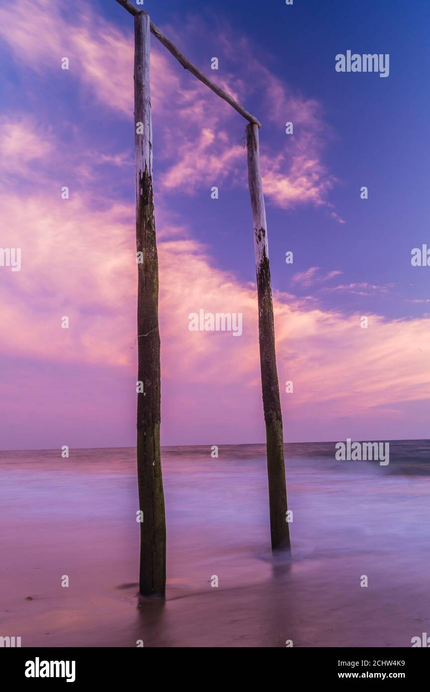 wooden poles on the beach at sunset glow Stock Photo - Alamy