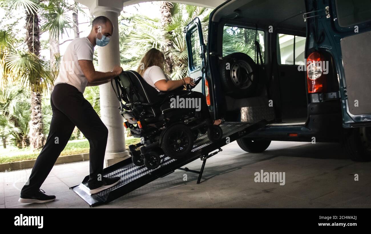 Assisting disabled woman on wheelchair with transport using accessible ...
