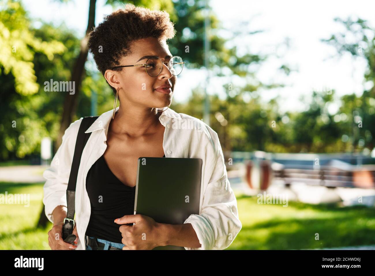 Photo of positive pleased african woman walking outdoors in park while ...