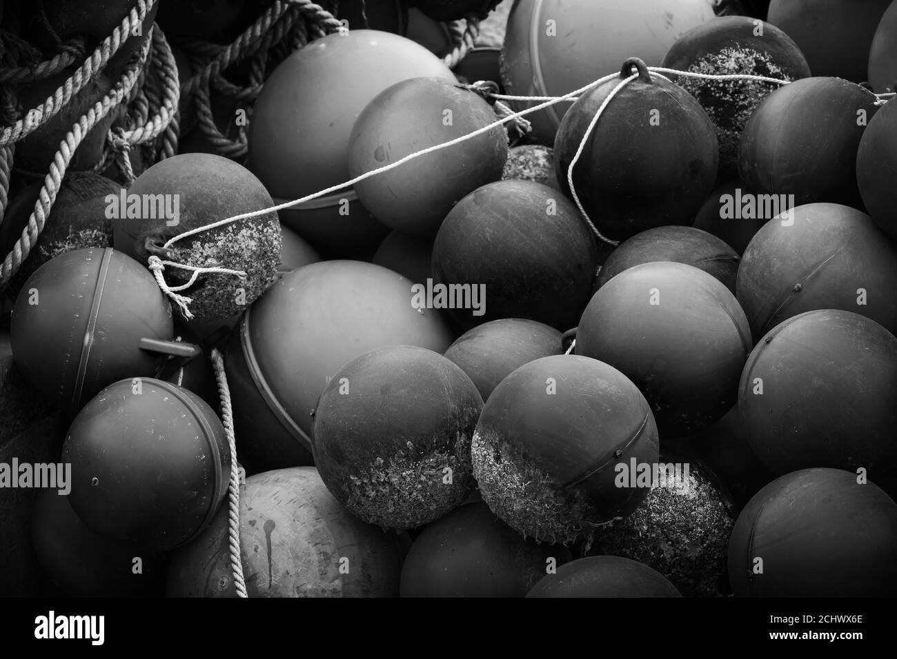 Spherical plastic floats of fishing nets lay in port. Black and white ...